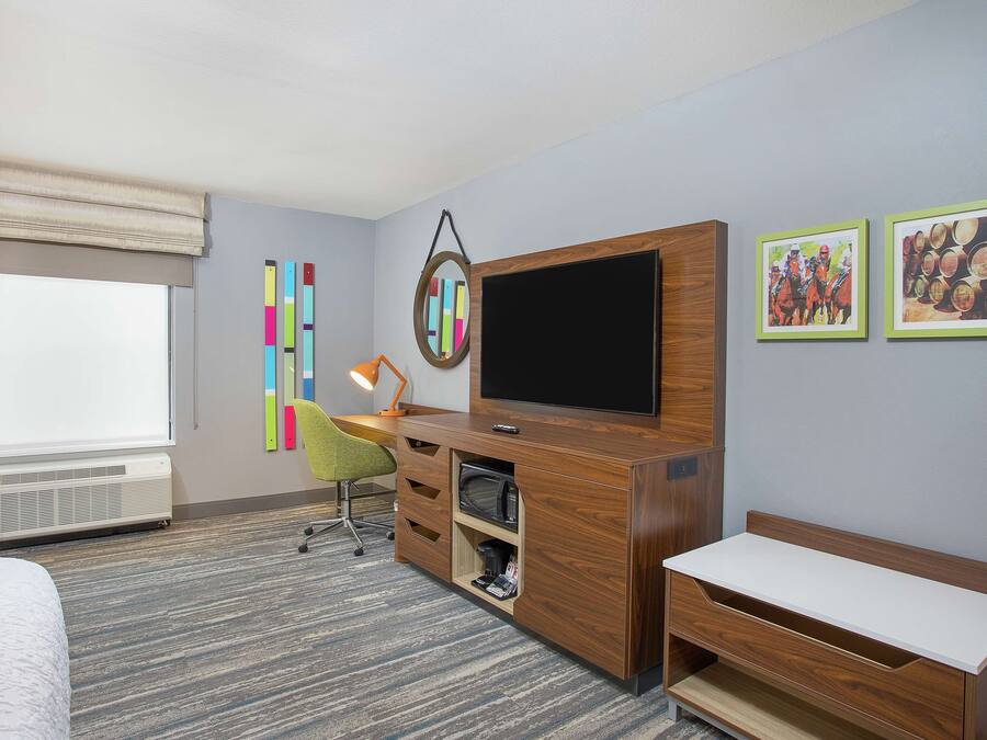 Quarto de hotel com uma cama grande, uma mesa com cadeira, televisão de tela plana, radiador e janela com vista.