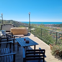 Um terraço com área de estar ao ar livre, lareira e vista para o mar e a cidade.