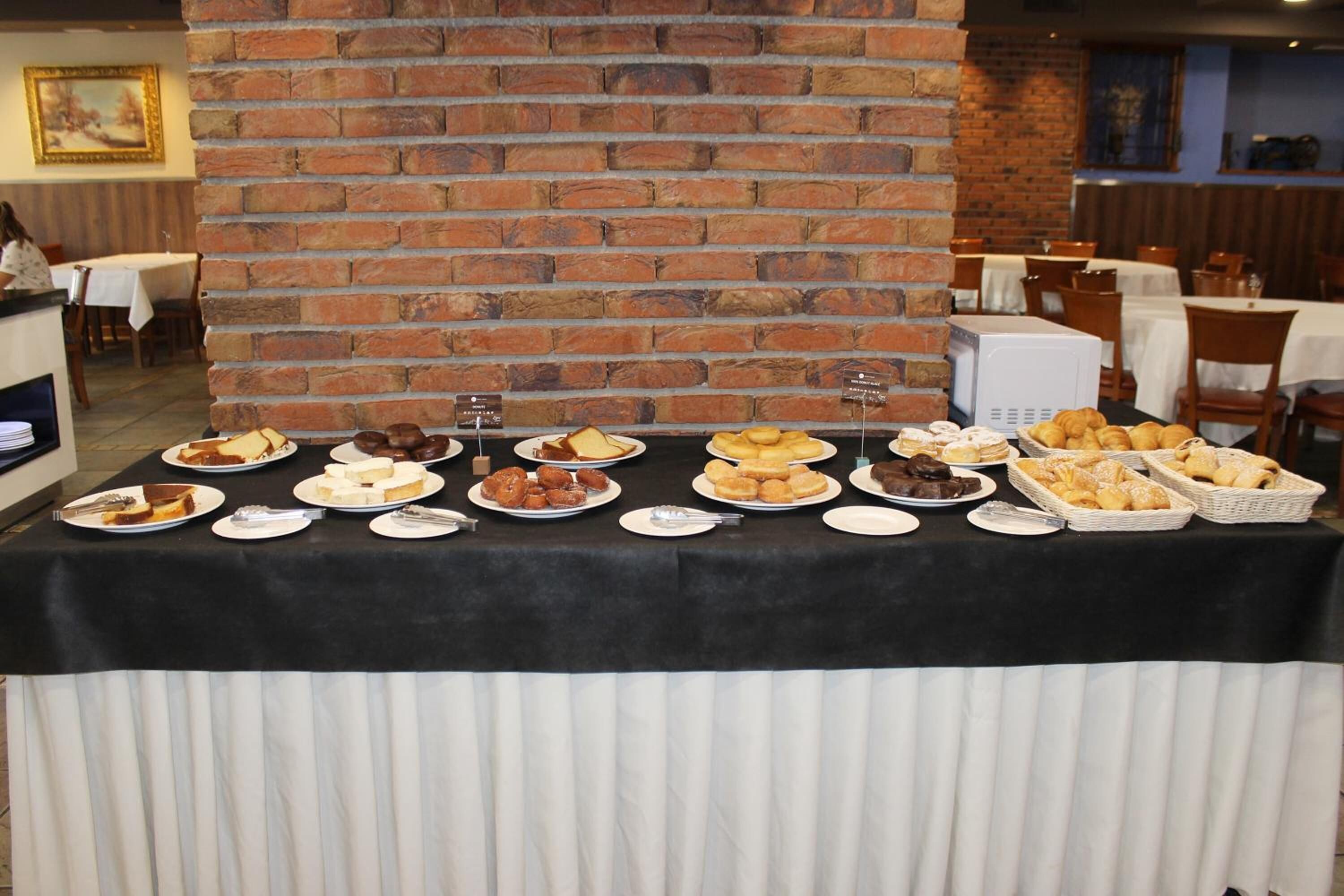 Mesa de buffet com diversos alimentos e um fundo de parede de tijolos.