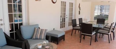 Uma sala de estar com mesa de centro de vidro, um sofá e um espaço de jantar com cadeiras e mesa.