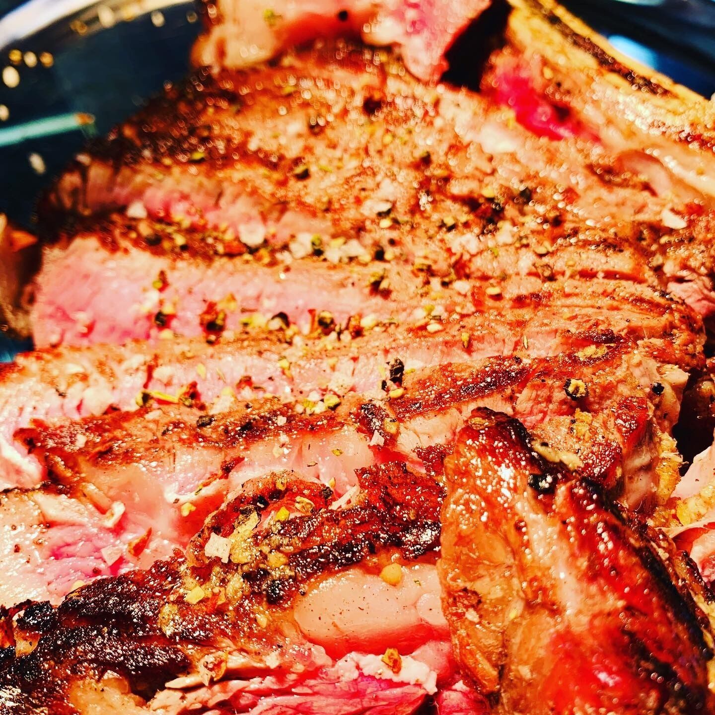 Close-up de um bife grelhado com tempero e marcas de grelha visíveis.