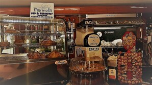 Vitrine de pastelaria com diversos produtos de panificação e acompanhamentos.