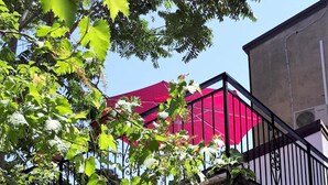 Um edifício com toldo vermelho, varanda com grades pretas e uma placa com a inscrição 'BB de Marinella'.
