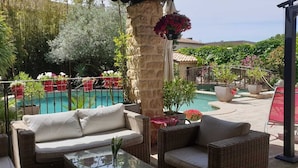 Um terraço no telhado com móveis de vime, piscina e plantas em vasos.