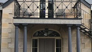 Um edifício com varanda, destacando-se pelo parapeito decorativo e estilo arquitetônico clássico.