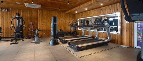 Uma academia com esteiras, saco de pancadas e diversos aparelhos de exercício.