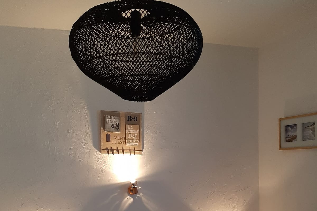 Quarto com uma cama, duas luminárias de cabeceira, uma luz embutida na parede e teto texturizado.