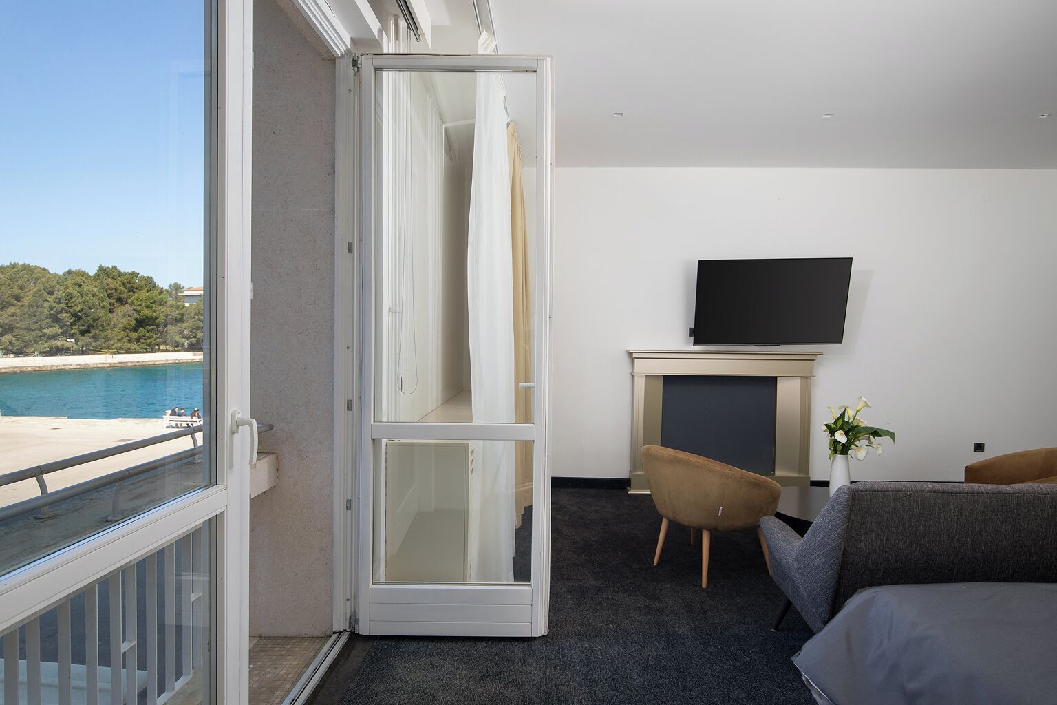 Quarto de hotel com varanda, televisão, cadeira e cama.