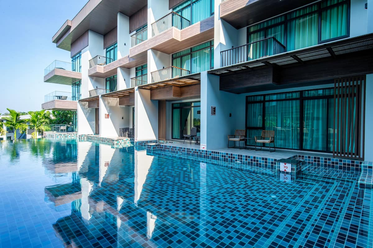 Um hotel moderno com uma grande piscina coberta, várias varandas e janelas amplas.