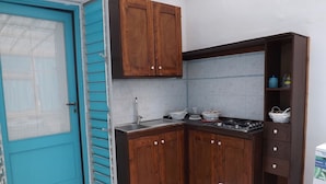 Uma cozinha compacta com armários de madeira, pia e fogão. Há uma mesa com uma tigela de frutas.