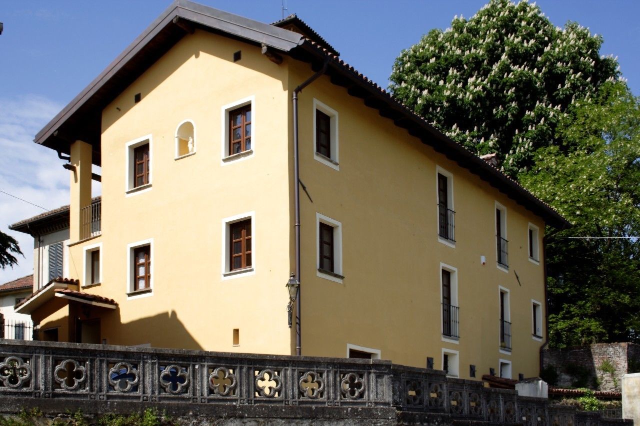 Um edifício de dois andares com fachada amarela, várias janelas e uma varanda.