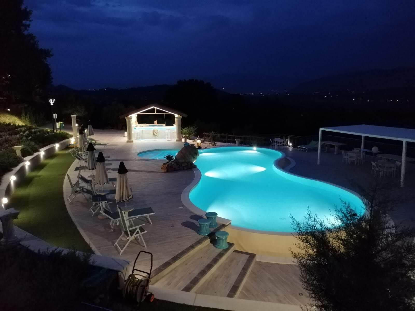 Piscina com área de bar e mobiliário para área externa.