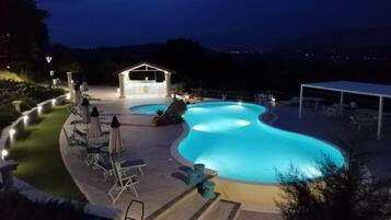 Piscina com área de bar e mobiliário para área externa.