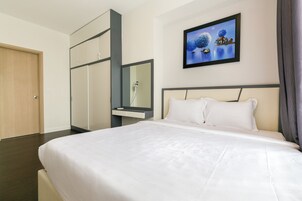Quarto de hotel com uma cama grande, um guarda-roupa, um espelho e uma pintura na parede.