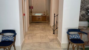 Um corredor com um banco de madeira, uma mesa de recepção e uma escada.