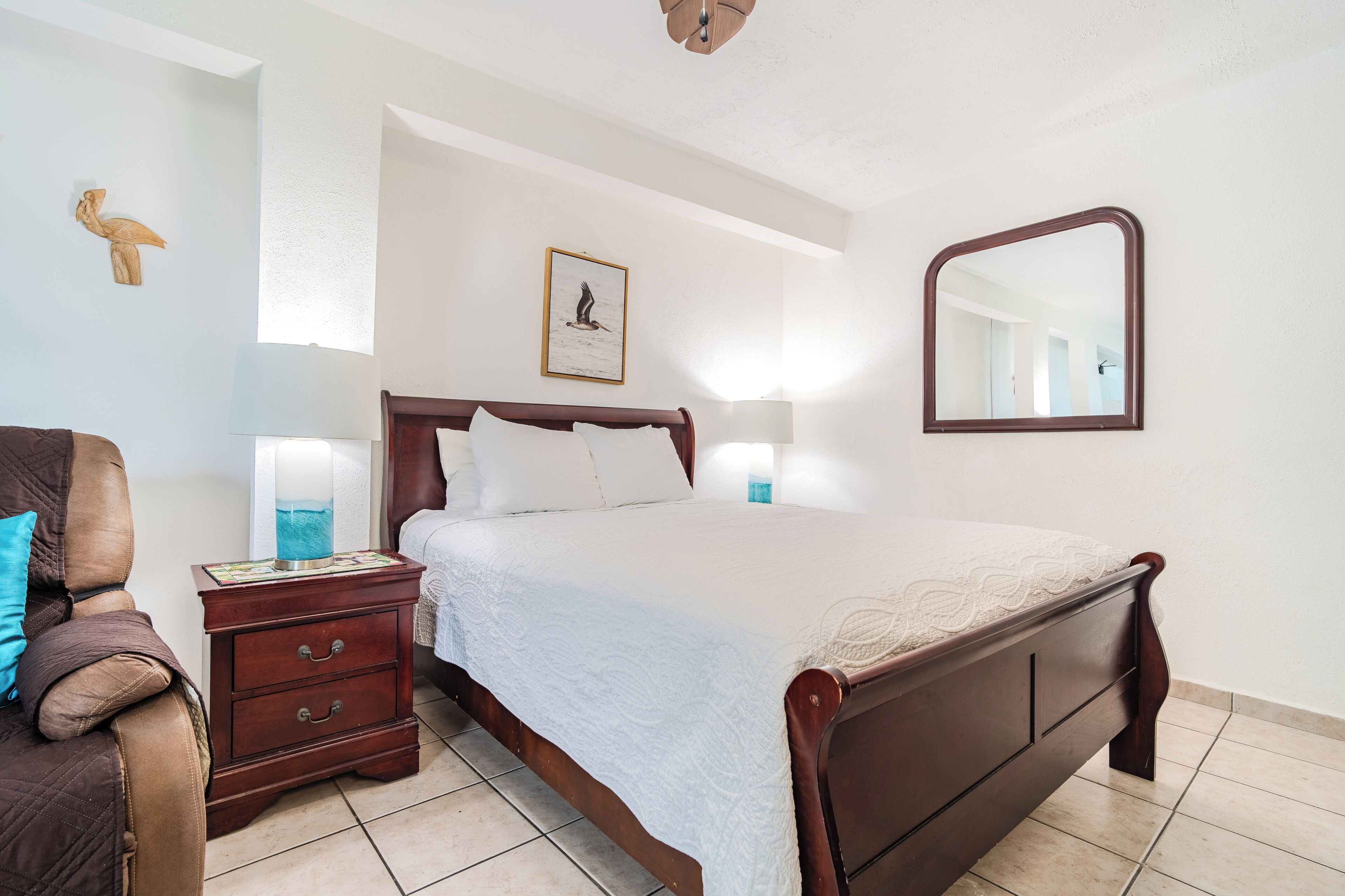 Quarto bem arrumado com uma cama de madeira, abajures, mesa de cabeceira e uma cadeira.