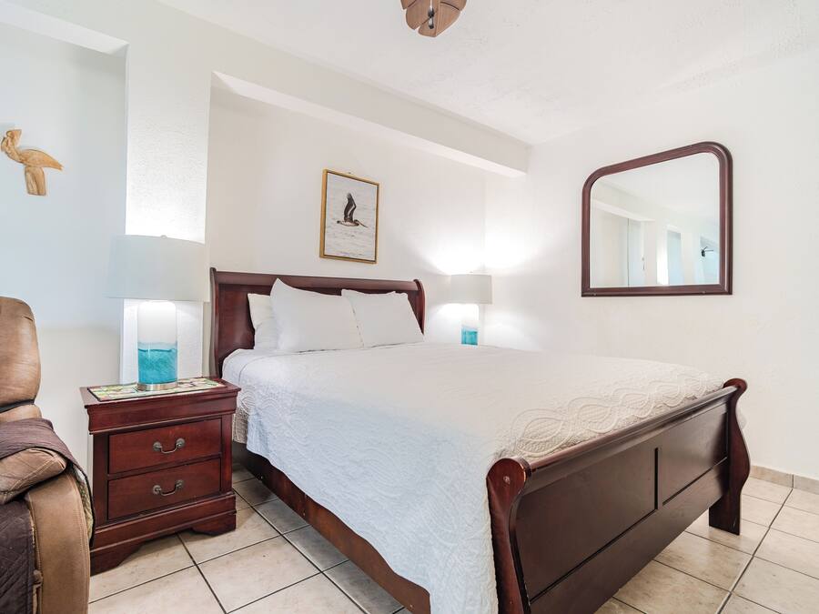 Quarto bem arrumado com uma cama de madeira, abajures, mesa de cabeceira e uma cadeira.