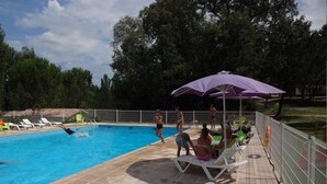 Uma área de piscina com espreguiçadeiras e guarda-sóis.
