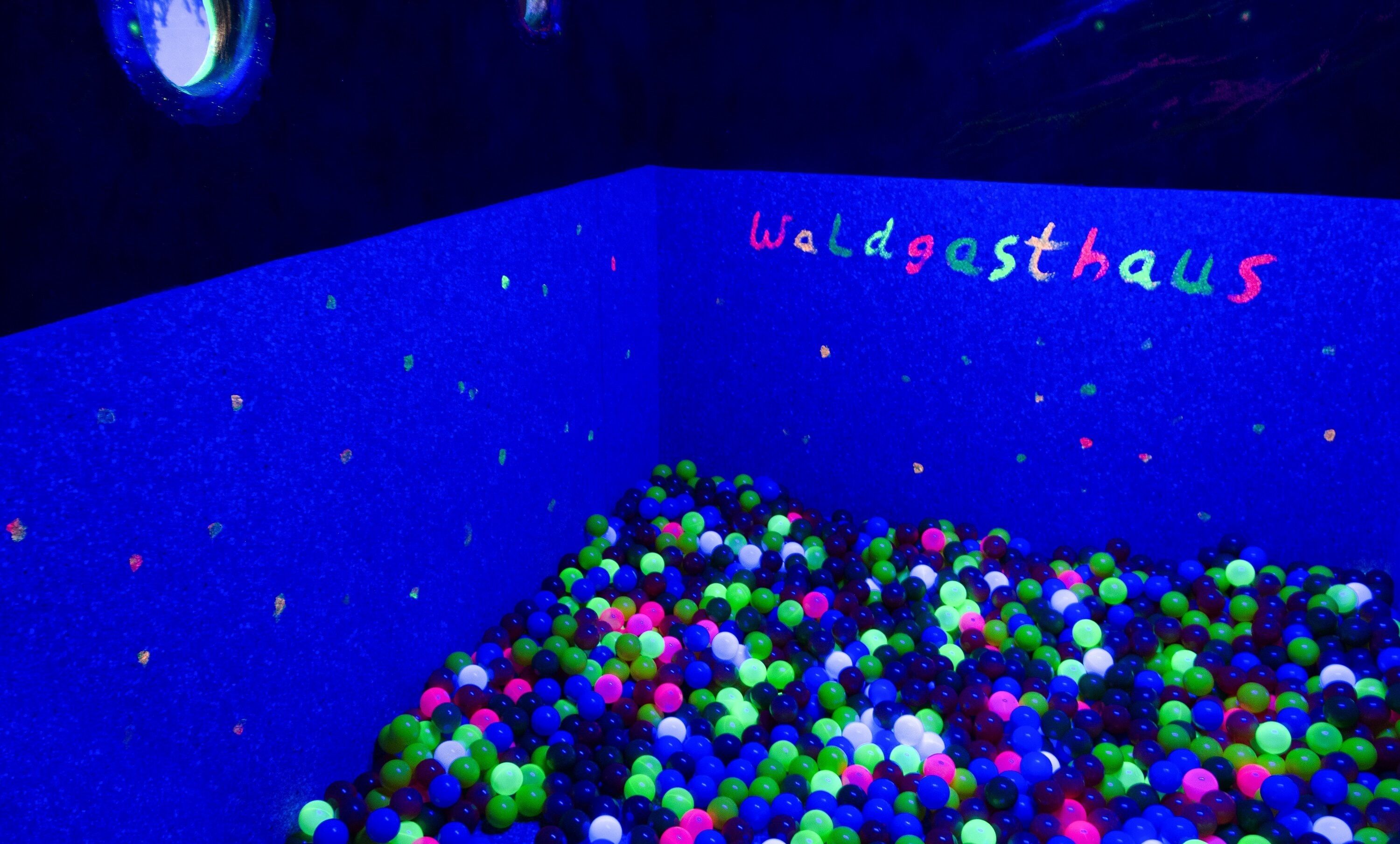 Um quarto cheio de bolas coloridas, com o texto "Weldgestehaus" visível na parede.