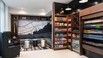 Uma área de estar moderna com assentos, um bar de petiscos e um refrigerador para bebidas.