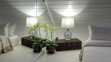 Quarto bem arrumado com uma cama, duas luminárias de cabeceira, um penteado e duas orquídeas em vasos.