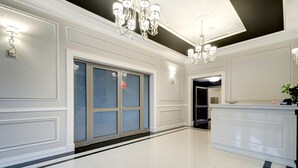 Um hall amplo com piso lustroso, balcão de recepção e um grande candelabro.