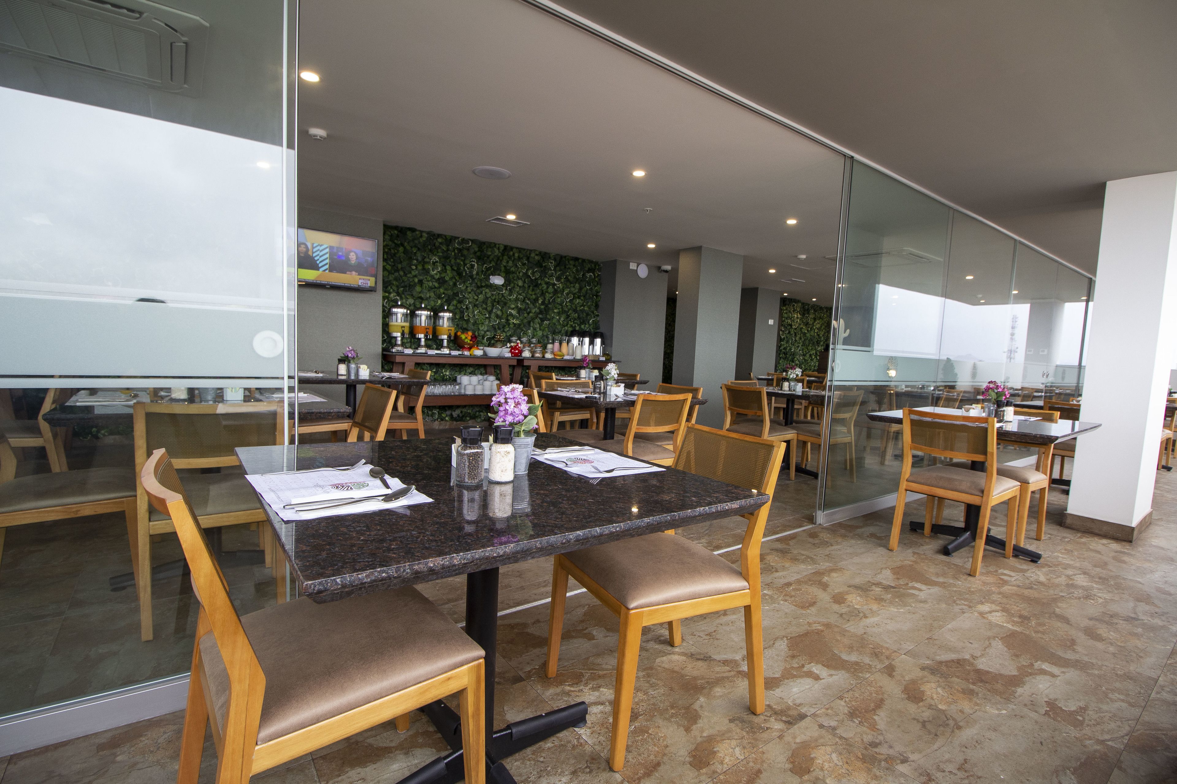 Uma área de refeições moderna com divisórias de vidro, cadeiras de madeira e uma mesa central com um menu.