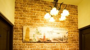 Parede de tijolos com um quadro de pontos turísticos da Itália, um lustre e uma porta.