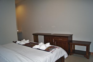 Quarto de hotel com uma cama, uma mesinha de cabeceira de madeira e um armário.