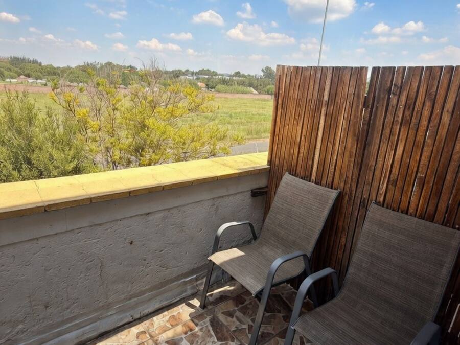 Varanda com duas cadeiras e vista para uma paisagem rural.