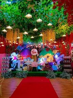 Palco com painel de plantas pendentes e luzes de fada, placa central com o nome 'Gia' e tapete vermelho que leva ao palco.