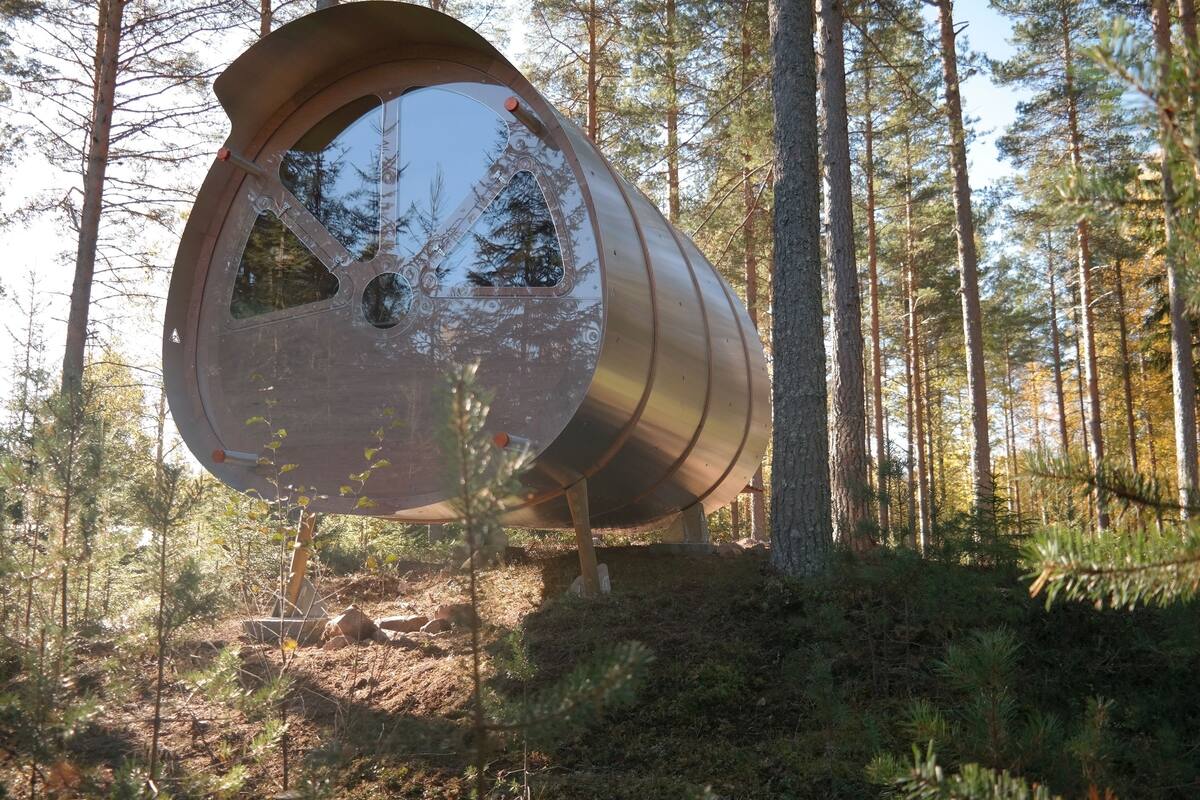 Uma estrutura de cabana em formato cilíndrico numa floresta.