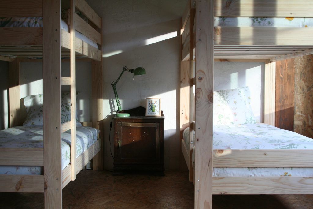 Quarto com beliche, escrivaninha e luminária.