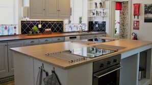 Uma cozinha moderna com ilha central, forno embutido e eletrodomésticos de aço inoxidável.