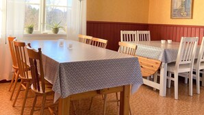 Uma área de refeições com uma mesa grande e cadeiras, uma janela com cortinas e um quadro na parede.