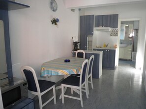 Cozinha compacta com área de refeições, incluindo micro-ondas, mini-geladeira e pia.