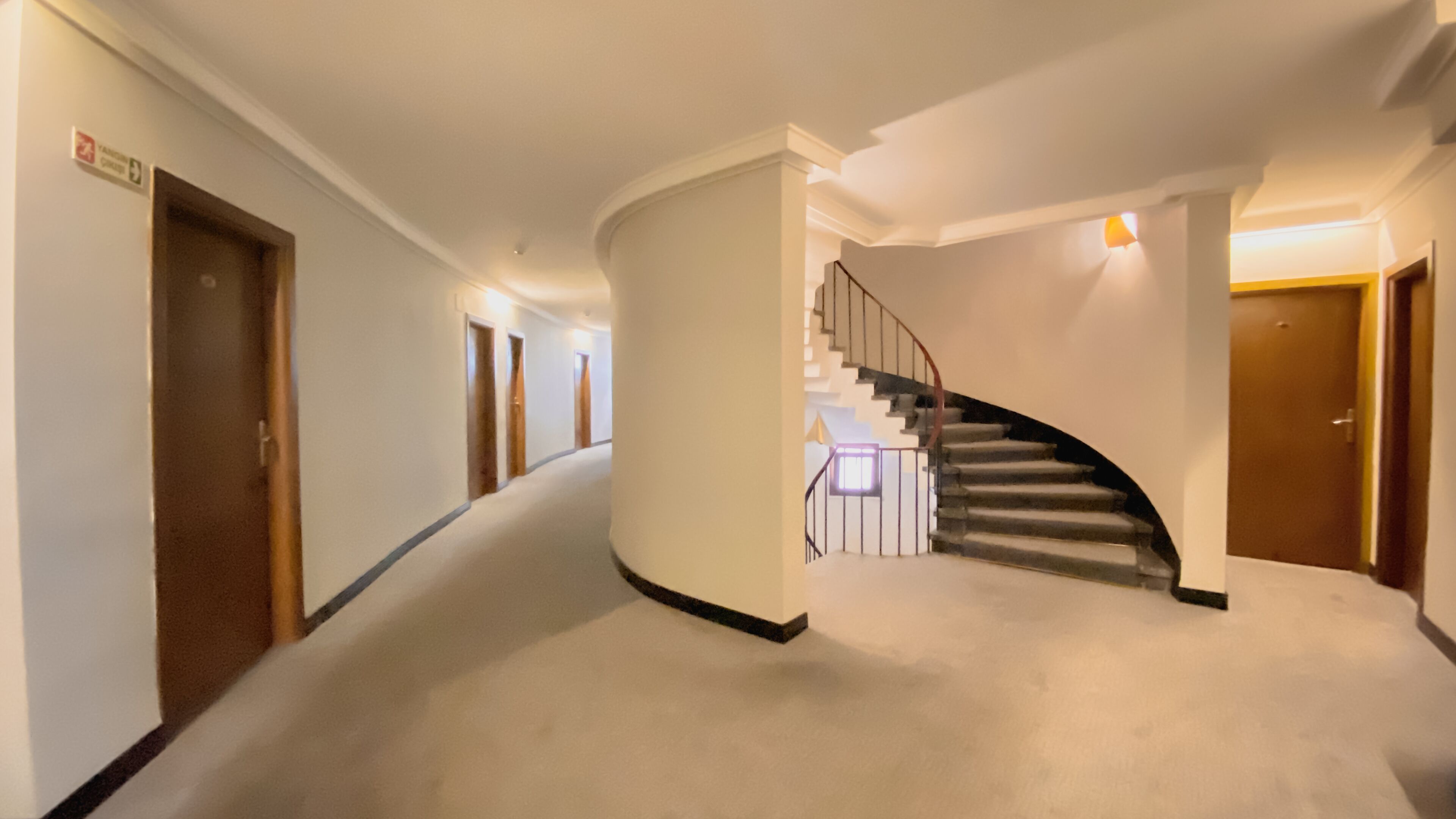 Um corredor de hotel com uma escadaria curva que leva a um patamar.