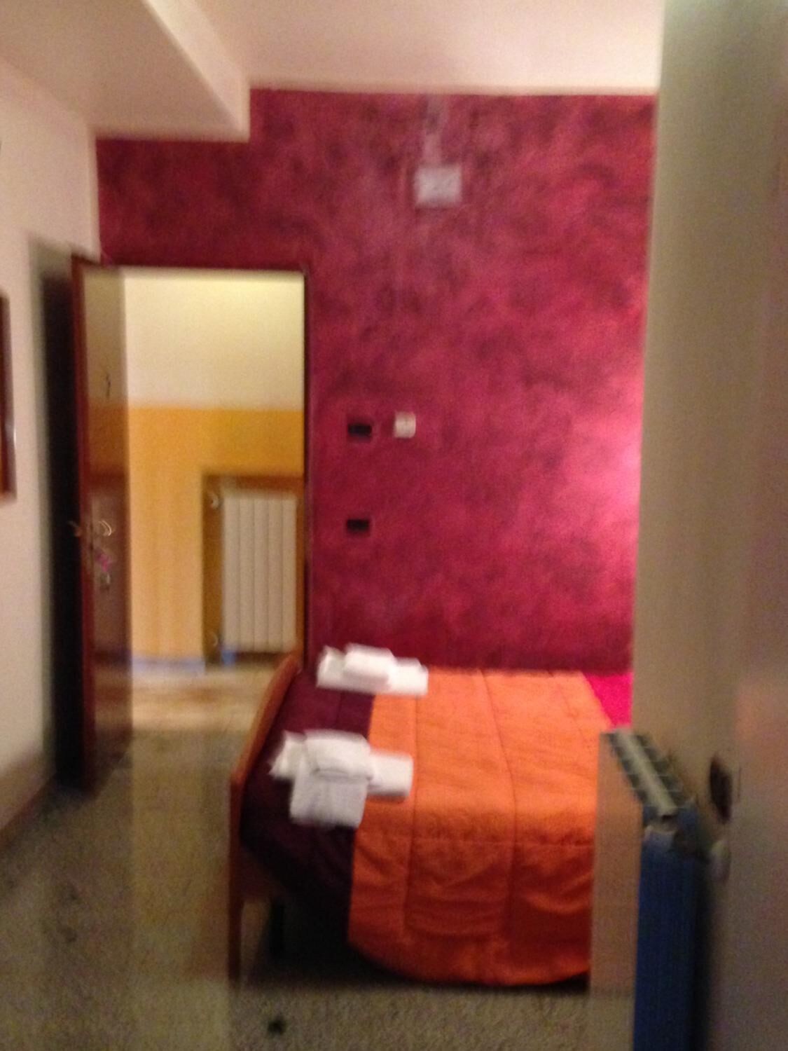 Quarto de hotel com uma cama, um espelho e um radiador.