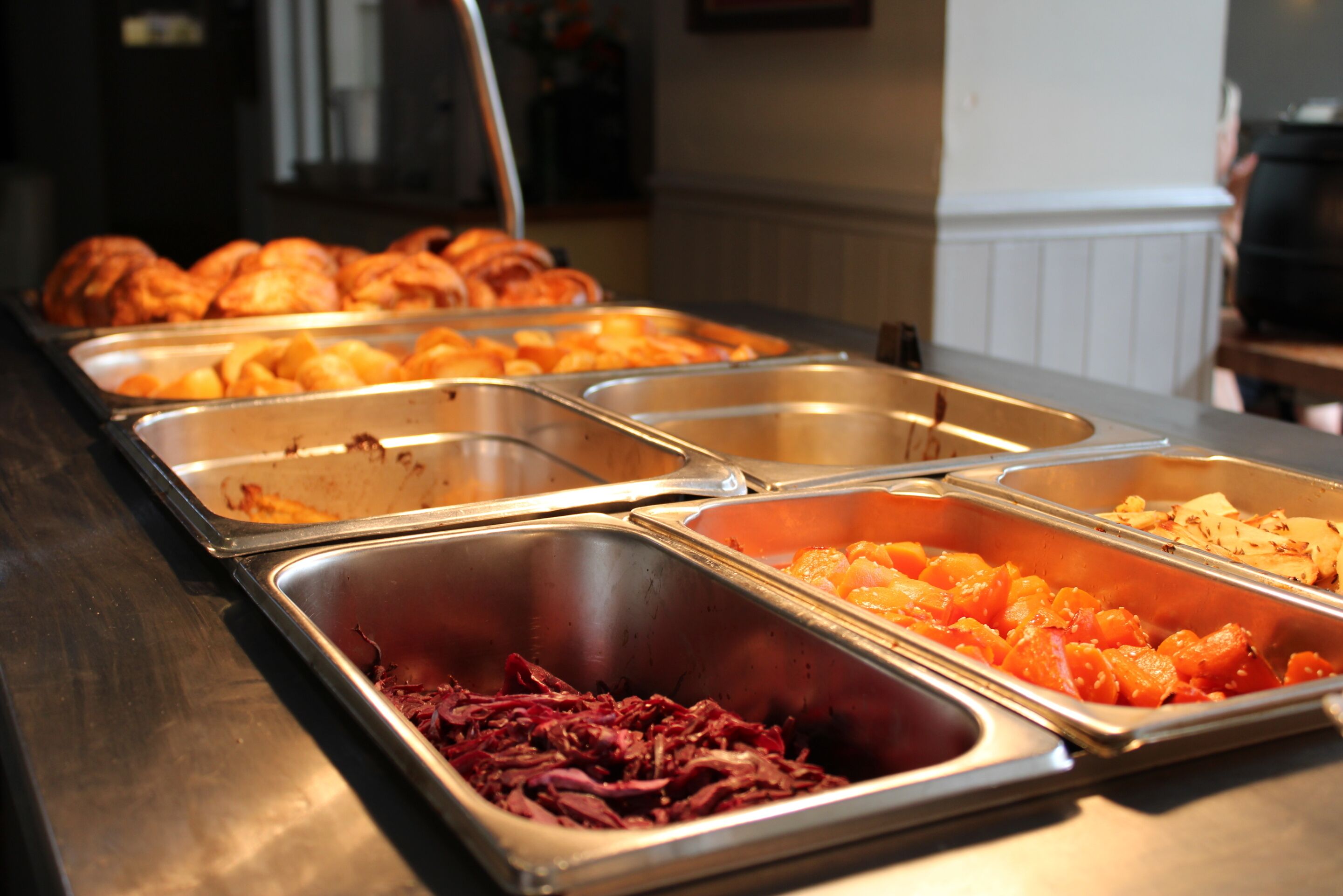 Buffet com diversos itens de comida, incluindo frutas, legumes e doces.