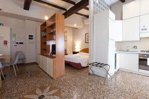 Quarto de hotel compacto com cozinha compacta, uma cama, um pequeno espaço para refeições e um banheiro.