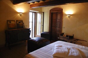 Quarto com cama, guarda-roupa de madeira, um banco e uma pequena mesa.