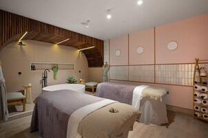 Um spa moderno com uma banheira grande, duas macas de tratamento, teto de madeira e prateleira com toalhas.
