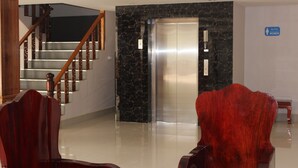 Um saguão com escada, elevador e placa indicando banheiro feminino.