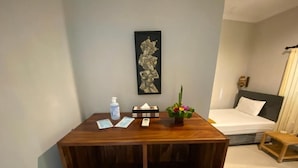 Quarto de hotel com uma escrivaninha de madeira, uma cama e uma obra de arte na parede.