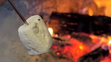 Um marshmallow espetado sobre uma fogueira.