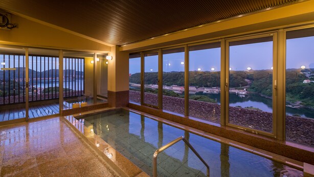 Uma piscina interior ampla com grandes janelas que oferecem vista para um rio e paisagem circundante.