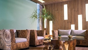 Uma sala de estar moderna com parede de madeira, uma planta grande e um conjunto de sofás.