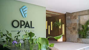 Uma área de recepção de hotel com uma placa indicando "OPAL SUITES" e um recurso de água com plantas.