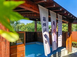 Uma estrutura de madeira com piscina, faixas com caracteres chineses e uma placa com texto.