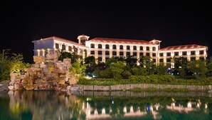 Um hotel grande e iluminado com uma piscina refletora na frente.